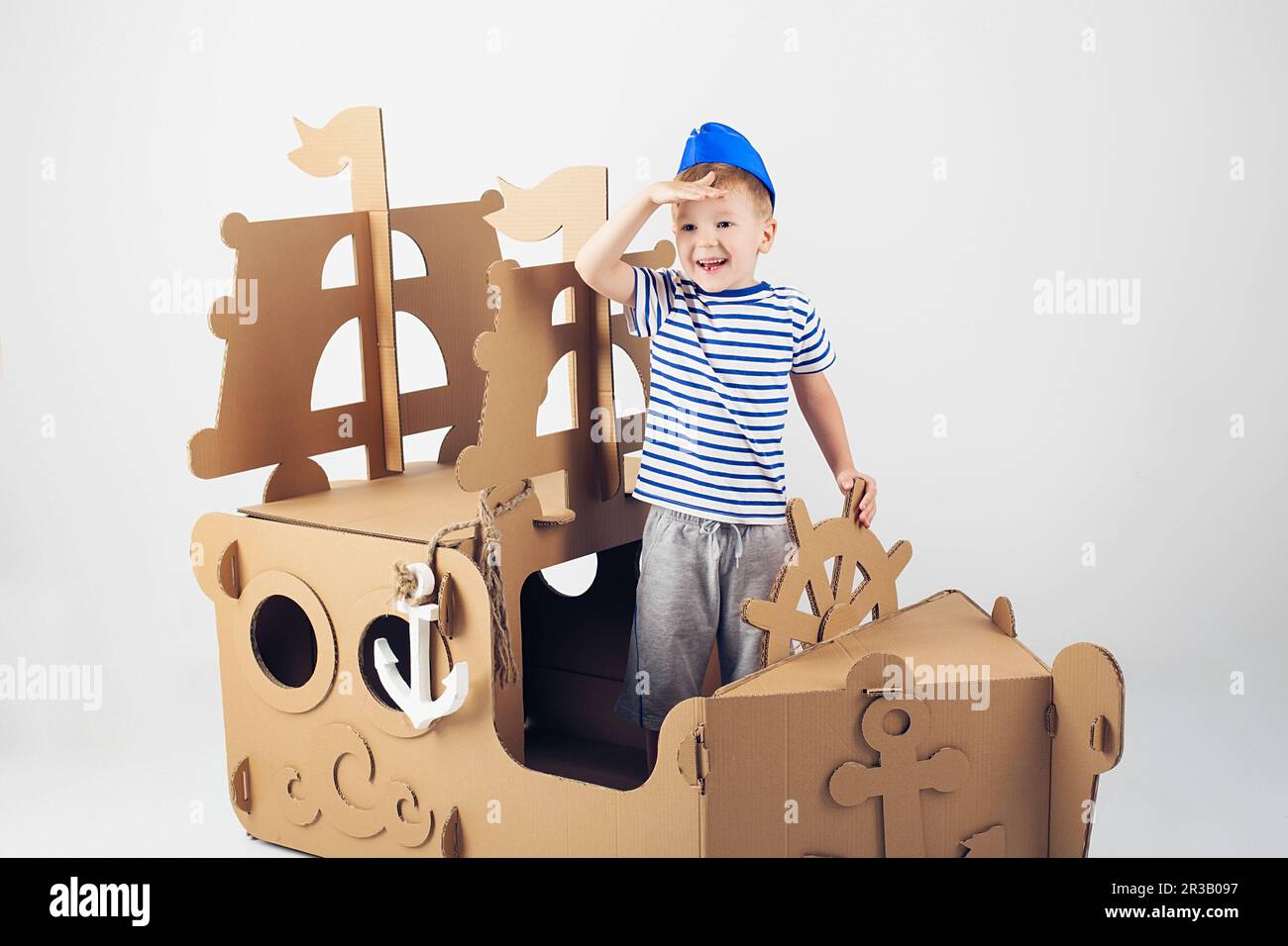 Petit garçon jouant avec un carton sur fond blanc. Les enfants sont ...