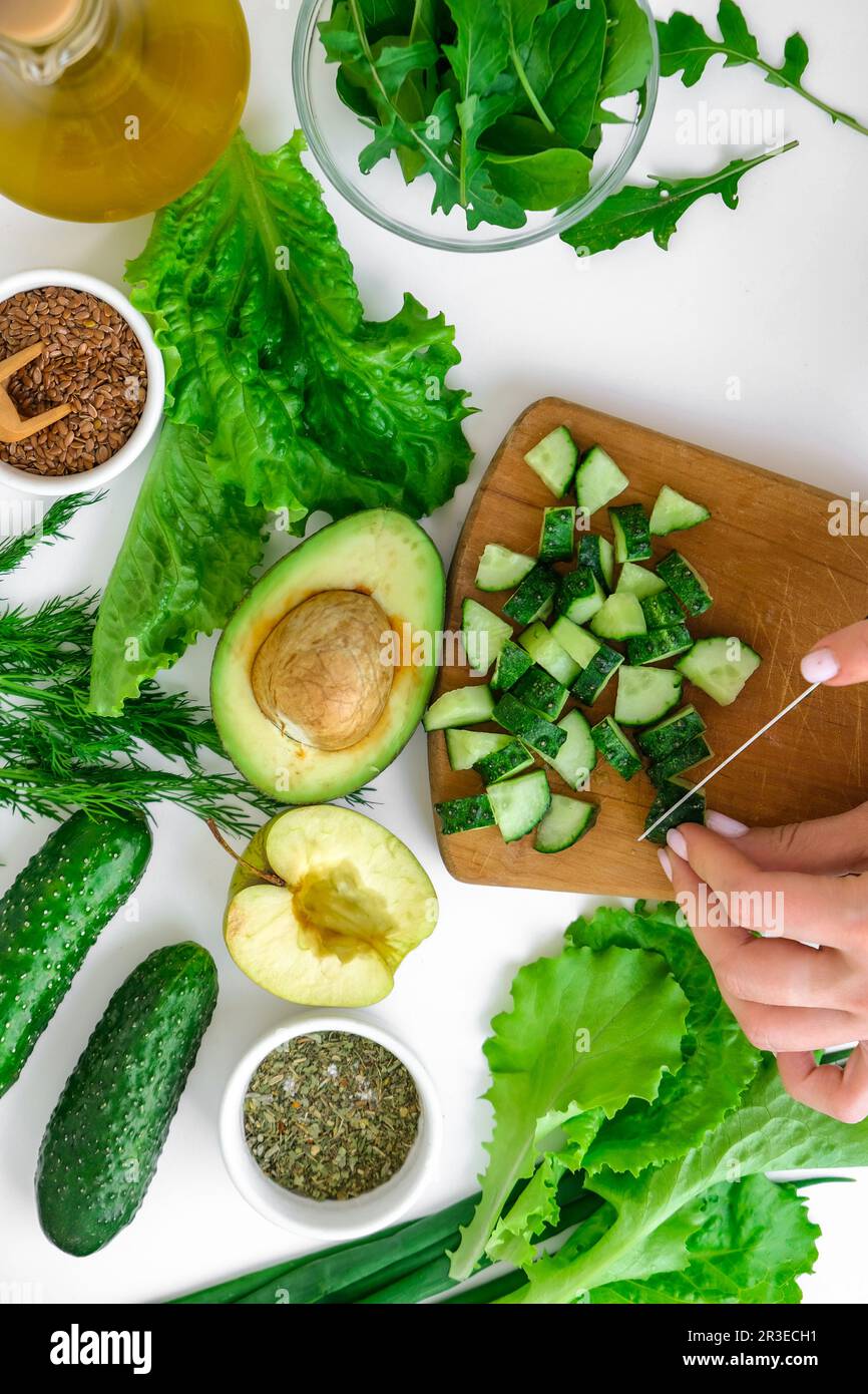 Femme cuisant de la salade de légumes verts frais et des herbes ...