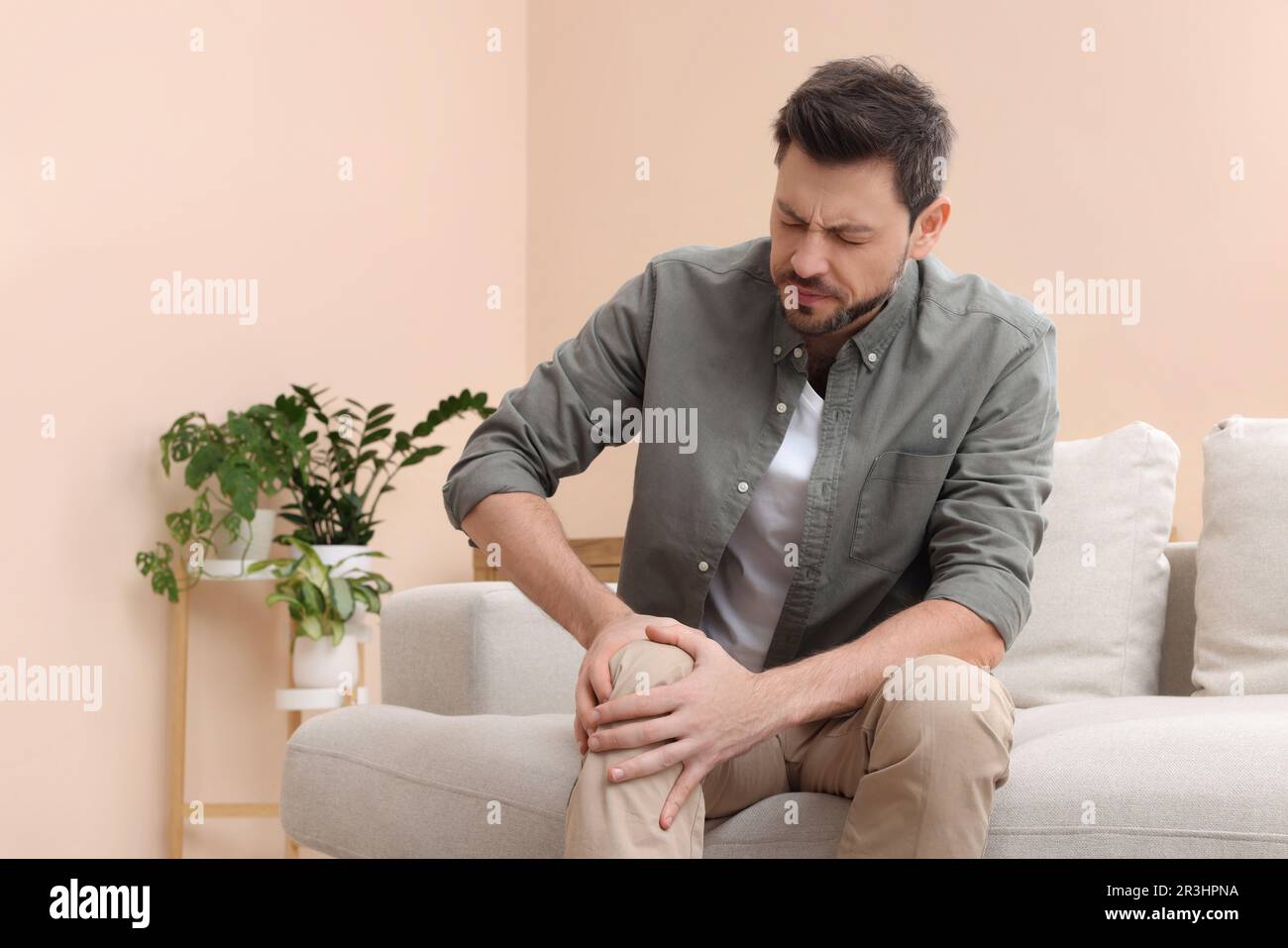 Homme souffrant de douleur dans sa jambe à la maison, espace pour le ...