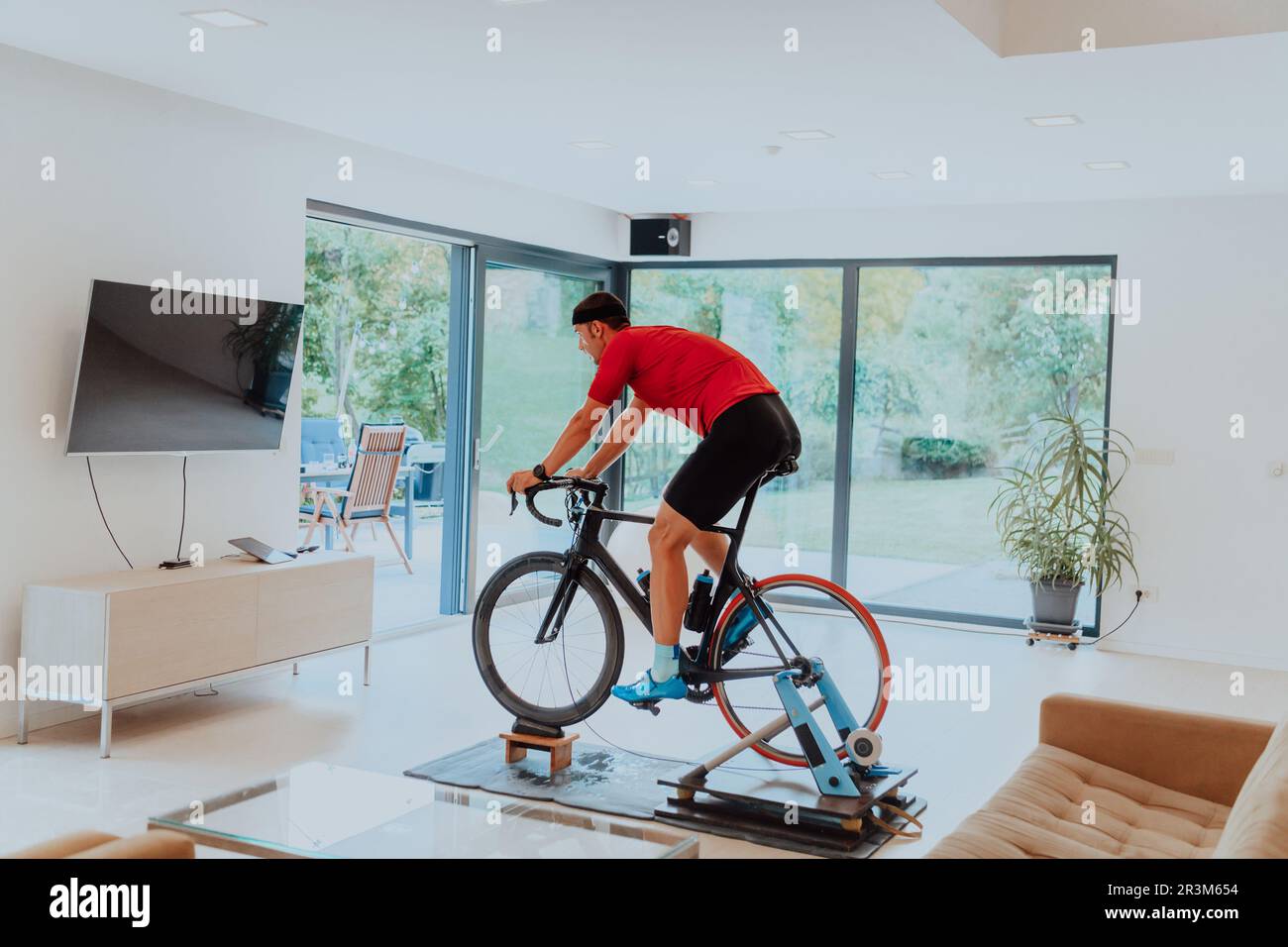 Un homme qui fait du vélo de triathlon sur une machine de simulation ...