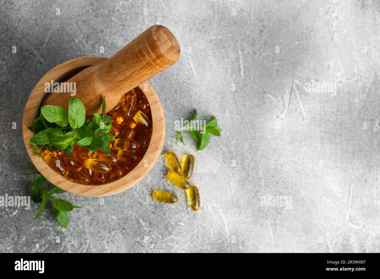 Mortier en bois avec herbes vertes fraîches et capsules sur table gris ...
