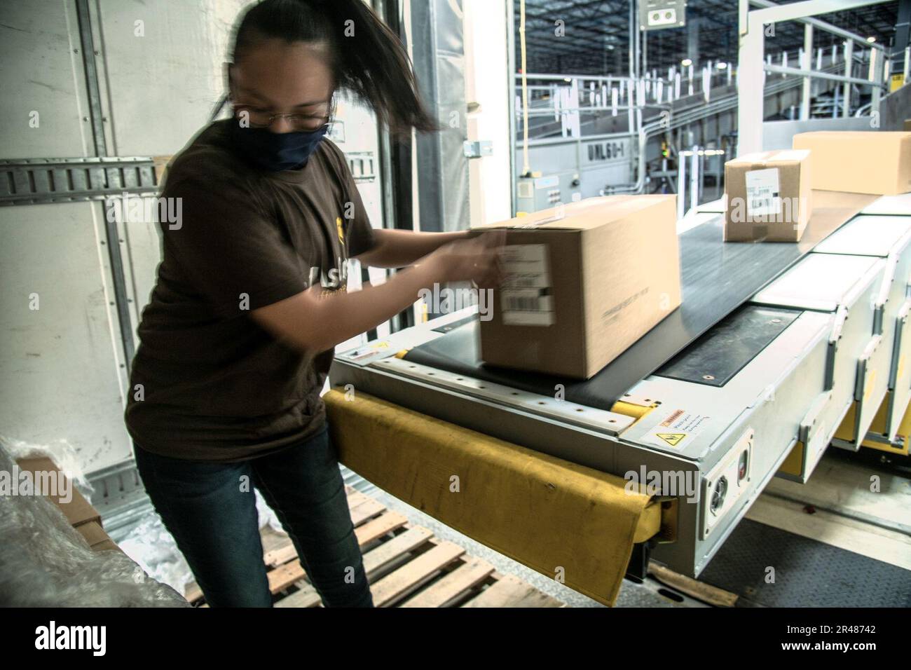 L'employé UPS décharge les boîtes du semi-remorque sur le tapis du ...