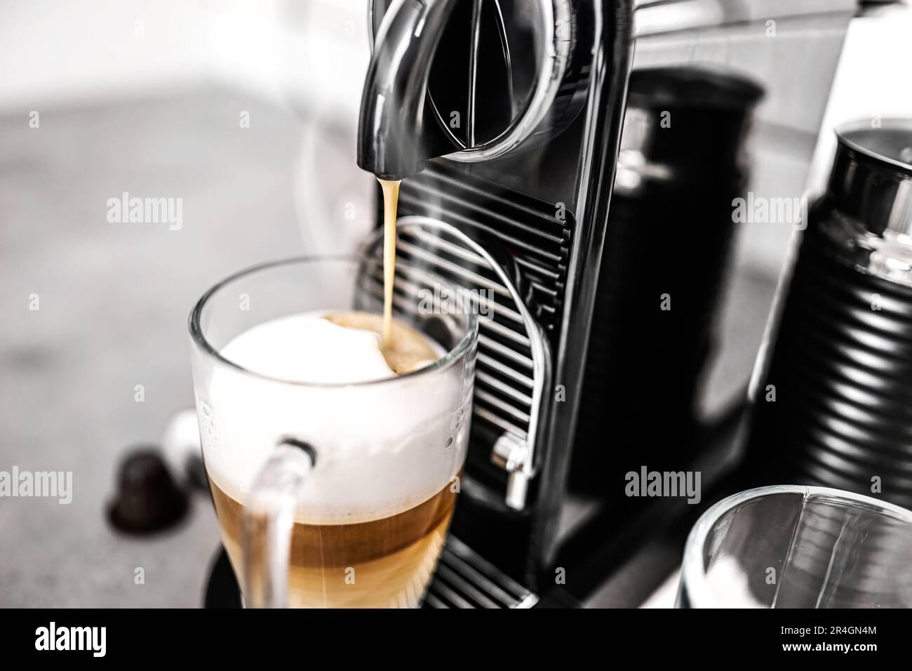 Machine à café avec capsules préparant du cappuccino dans une tasse ...