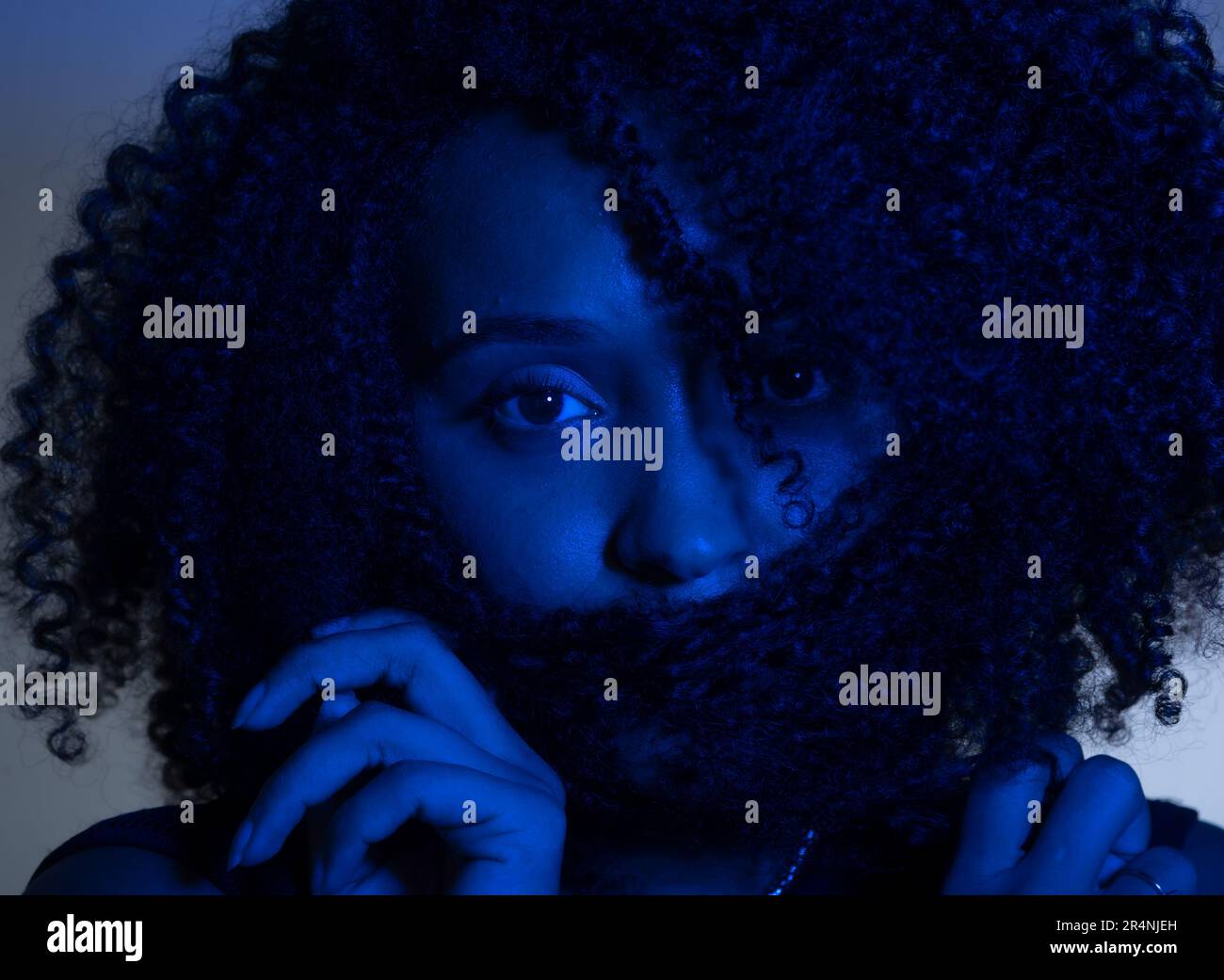 Portrait en gros plan d'une belle jeune femme avec des cheveux bouclés sur son visage. Isolé sur ...