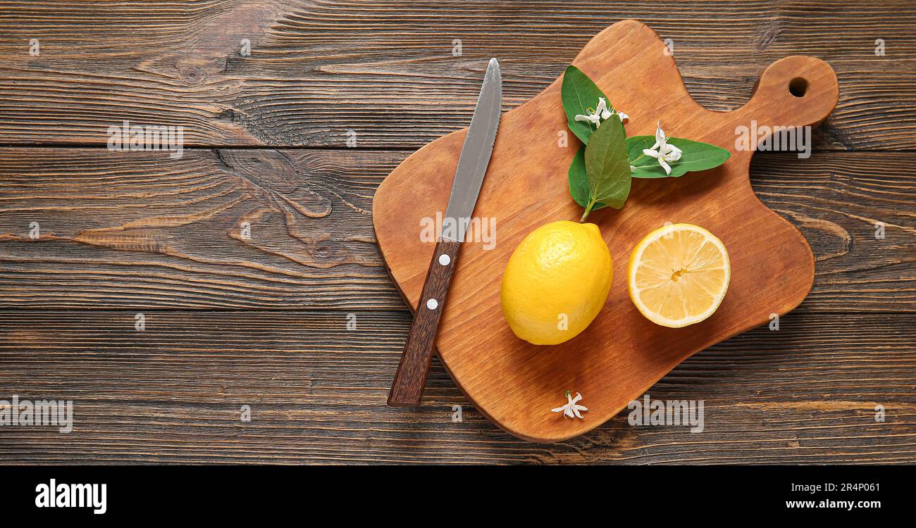 Planche avec citrons frais, couteau, fleurs et feuilles sur fond de ...