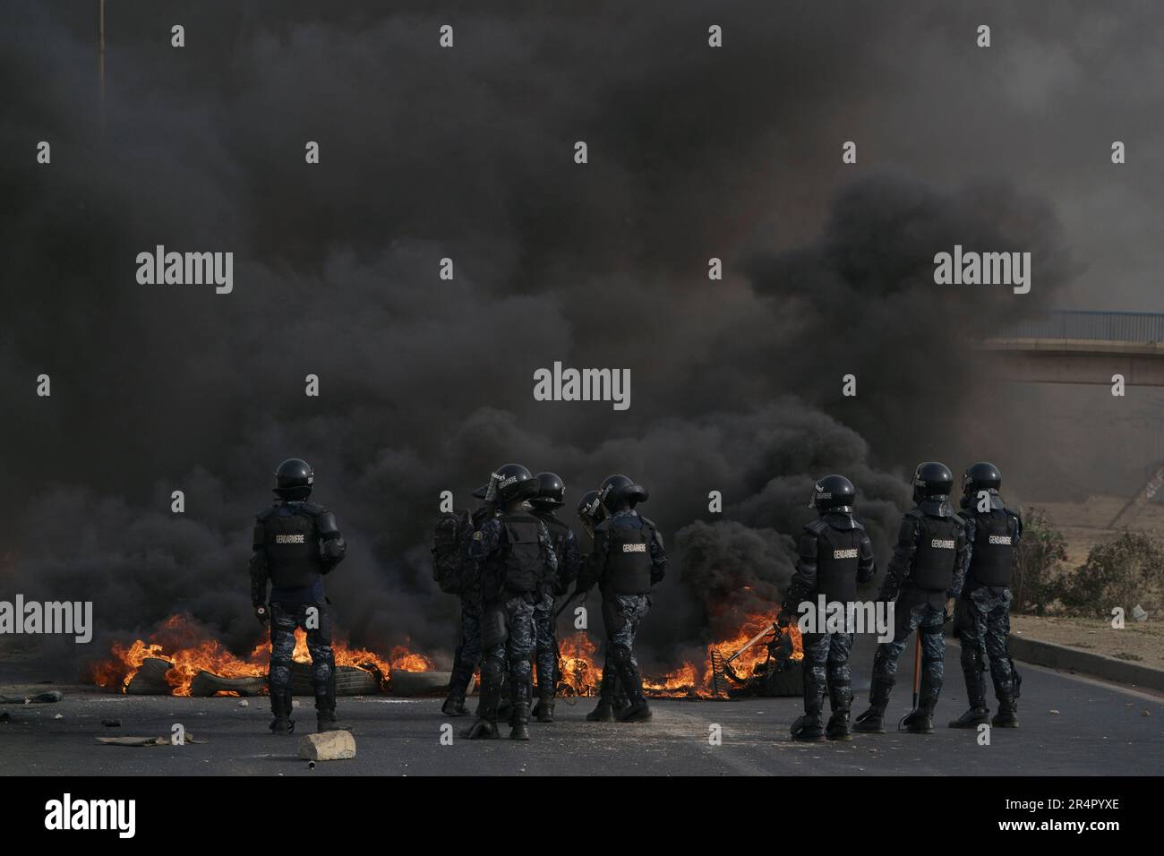 Riot police officers stand in front of tires set on fire during a ...