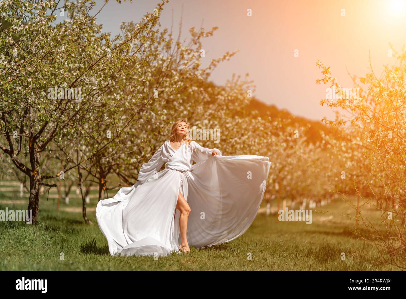Femme blanc robe parc. Une femme vêtue de blanc traverse un verger de ...