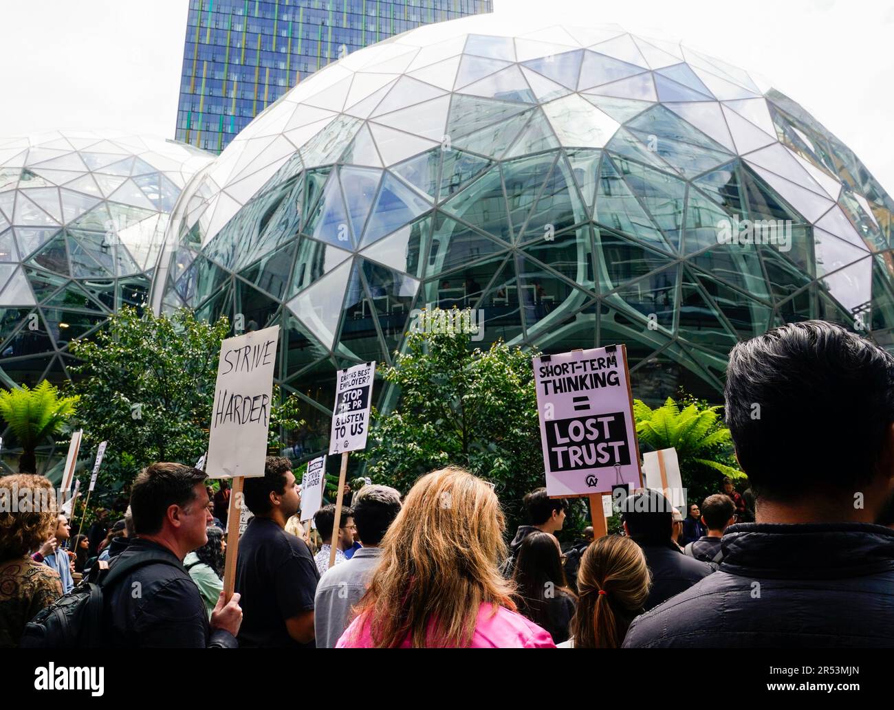 Amazon corporate workers hold picket signs in front of the Amazon ...