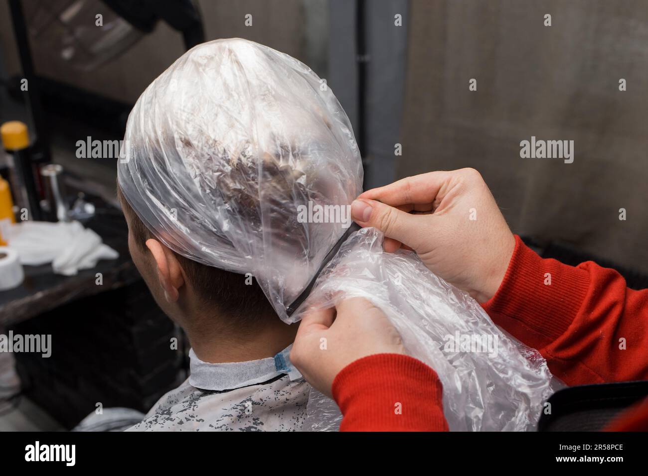 Gros plan des mains du coiffeur fixant un film protecteur sur la tête d ...