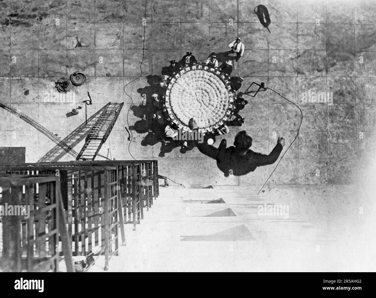 Dans le 1930s. Un homme saute d'un bâtiment dans une feuille de ...