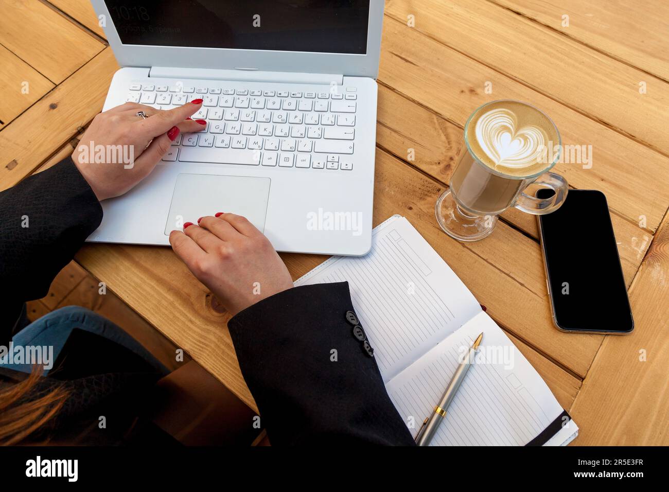 Mains de femmes avec manucure rouge sur l'arrière-plan d'un ordinateur portable blanc. La fille ...
