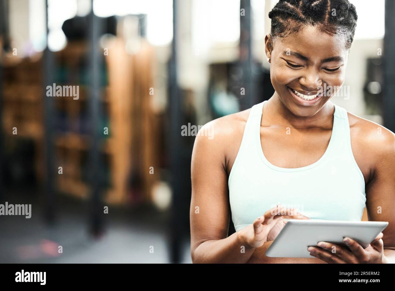 Bonne femme noire avec une tablette et dans une salle de gym avec un ...