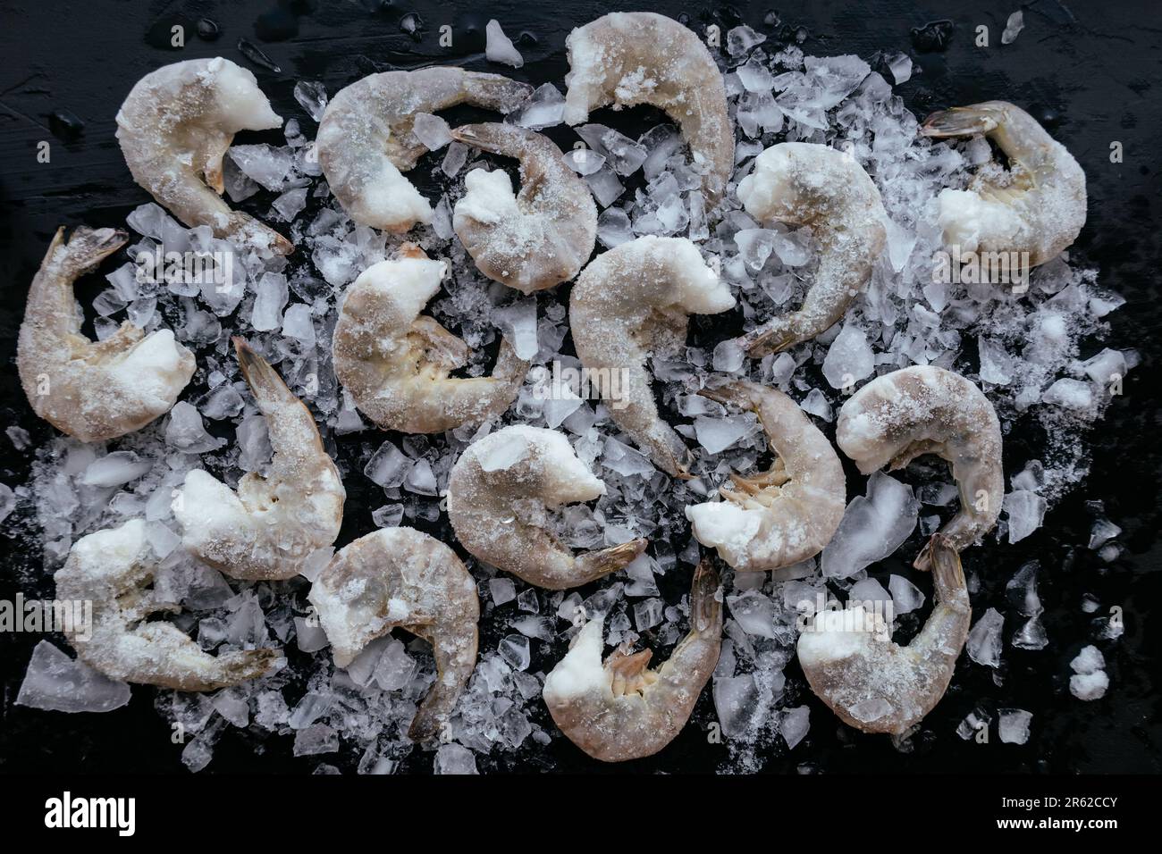 Fruits de mer sur glace écrasée et surface sombre. Crevettes crues ...