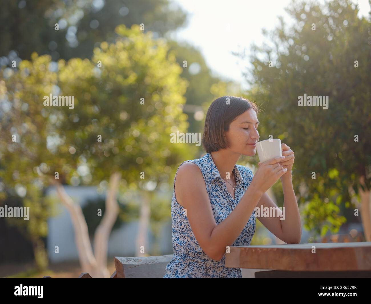 La femme boit du café, la routine du matin près de sa petite maison. Première propriété. Petit ...