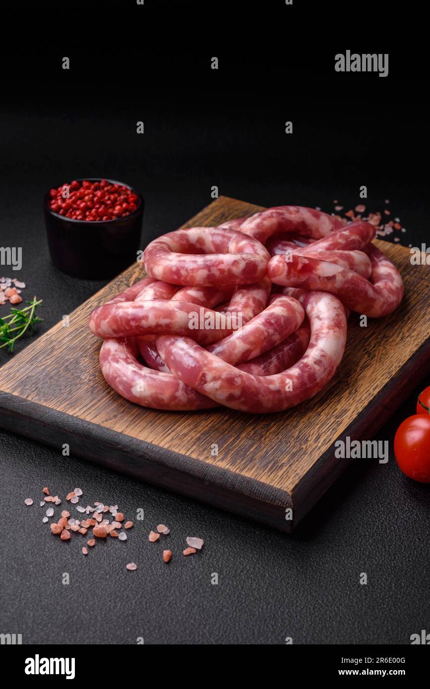 Saucisses crues de porc ou de boeuf avec sel, épices et herbes sur fond de béton foncé Photo ...