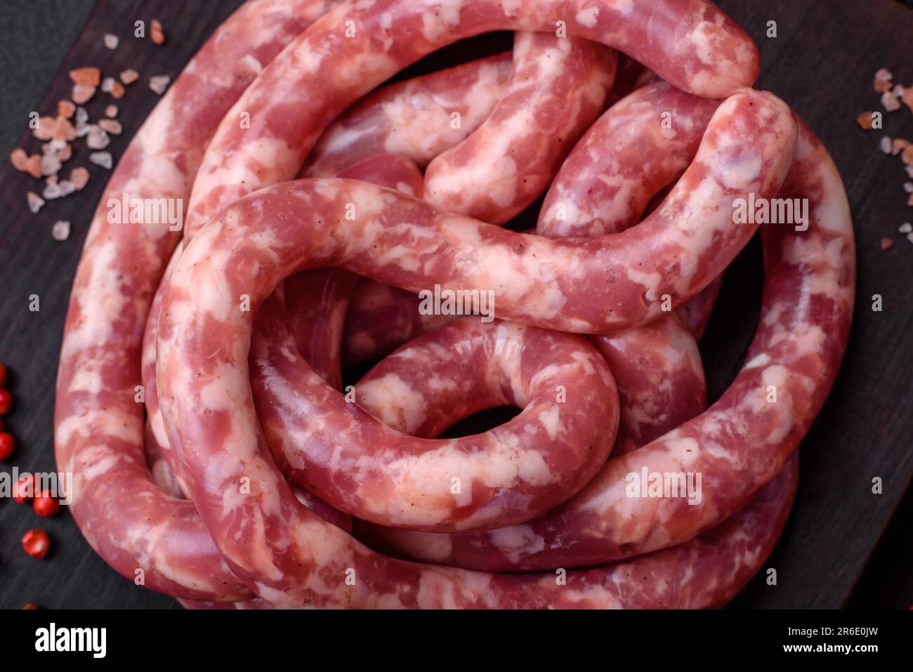 Saucisses crues de porc ou de boeuf avec sel, épices et herbes sur fond de béton foncé Photo ...