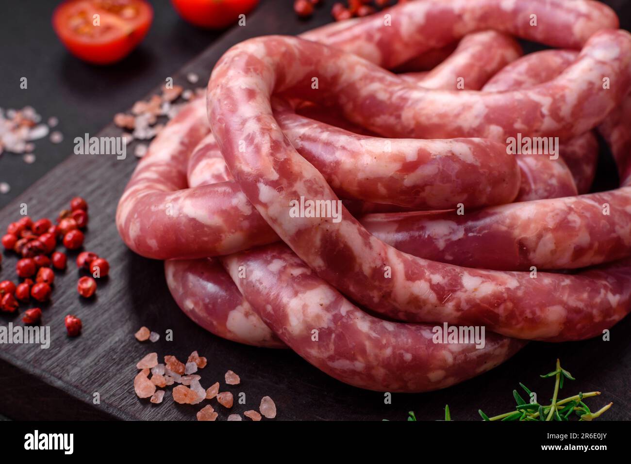 Saucisses crues de porc ou de boeuf avec sel, épices et herbes sur fond de béton foncé Photo ...