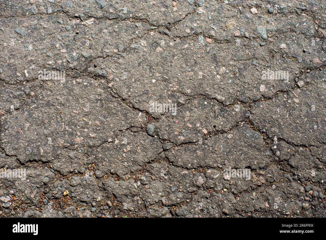 Un réseau de fissures noires sur la surface de l'asphalte. Texture de ...