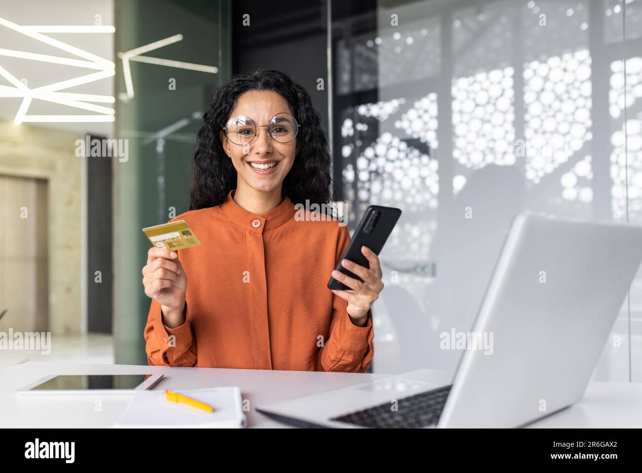 Portrait d'une femme d'affaires latino-américaine assise à un bureau dans le bureau et tenant ...