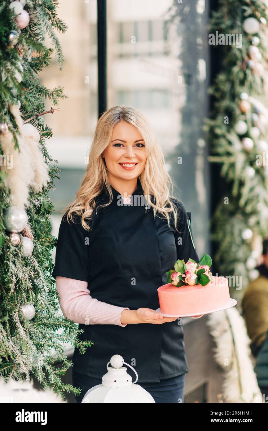 Portrait d'une femme boulangère joyeuse debout à côté de la façade de ...