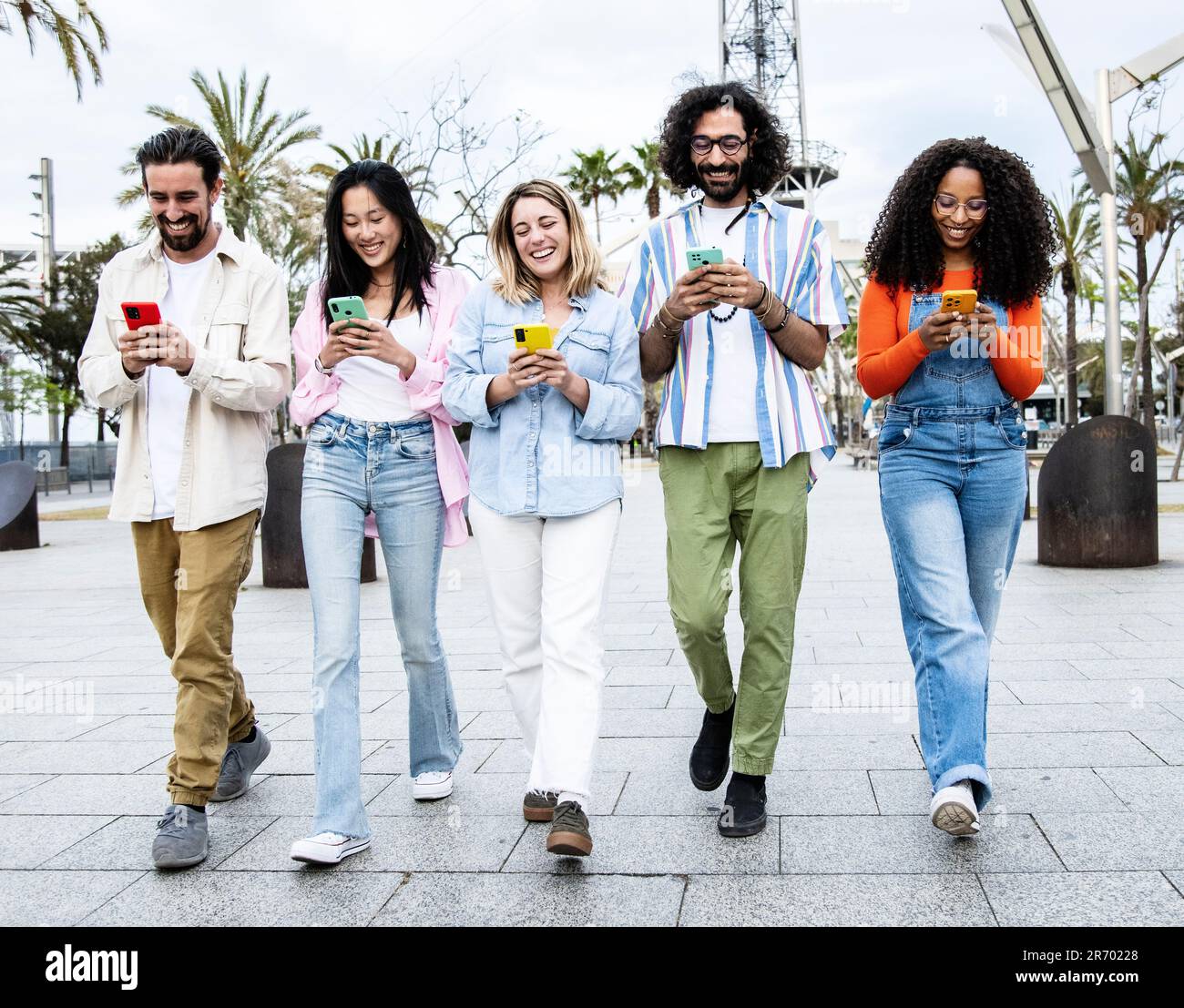 Groupe multiethnique d'amis envoyant des SMS sur leur smartphone tout ...