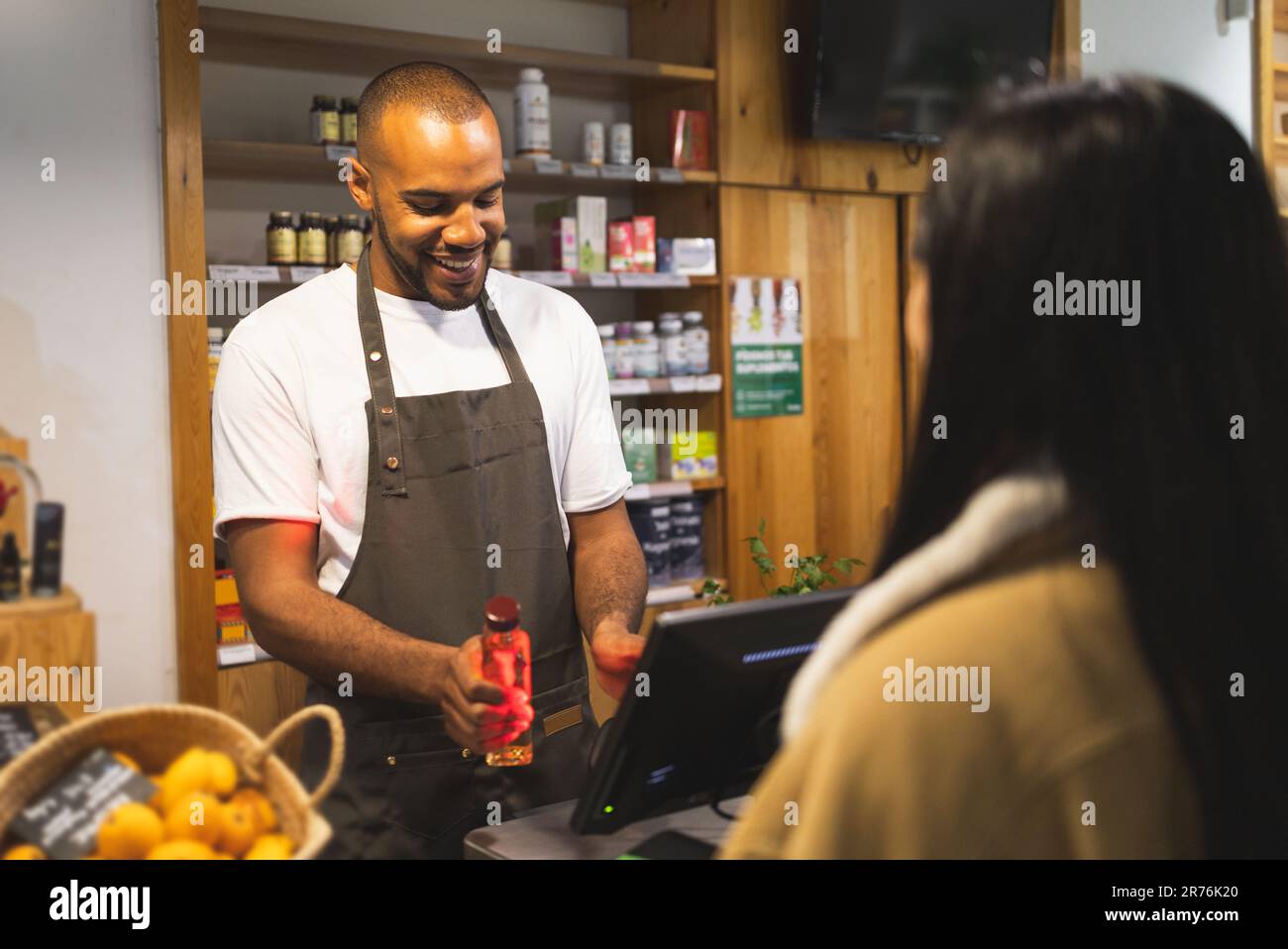Un jeune vendeur afro-américain positif en tablier souriant et donnant ...