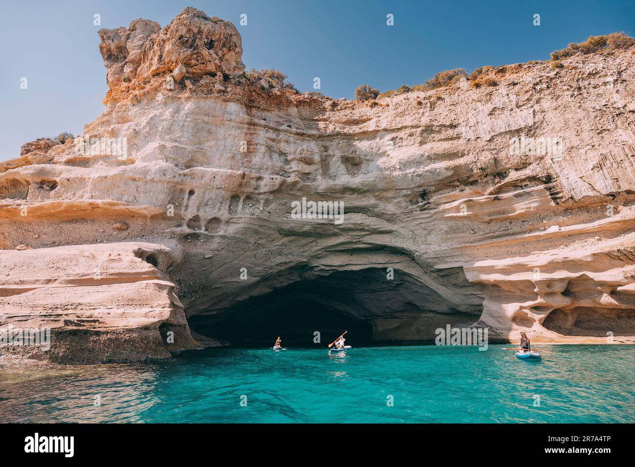 Groupe de boardeurs entre dans une immense grotte calcaire sur une côte ...