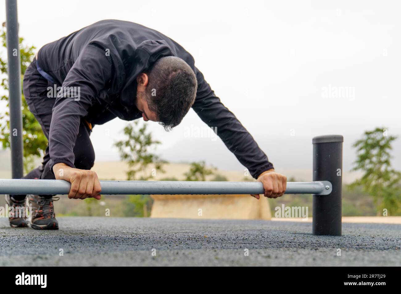 Jeune homme barbu habillé en entraînement noir sur une barbell sur le ...