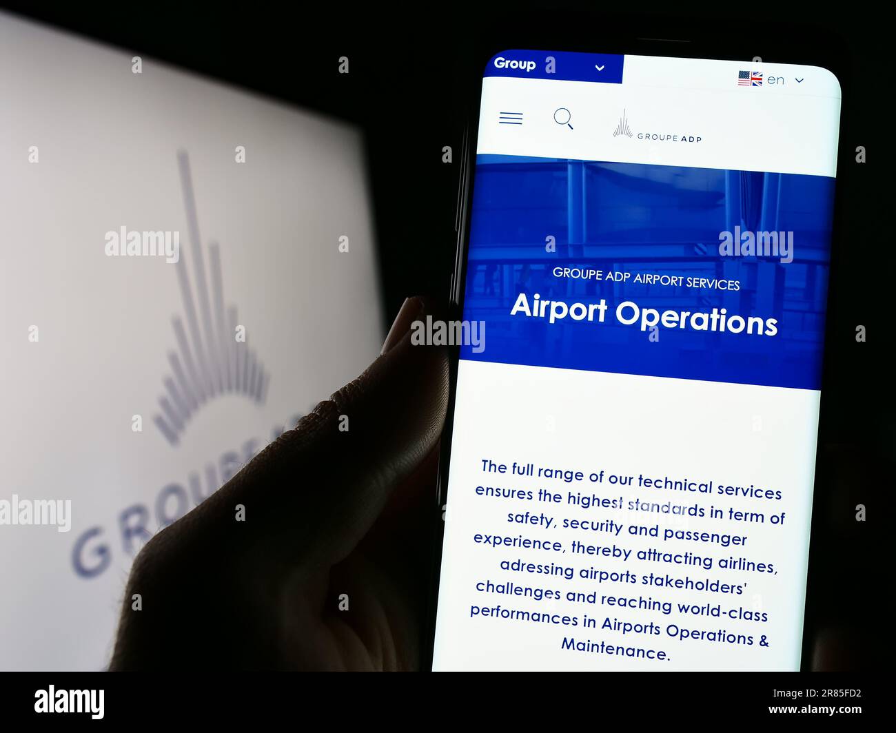 Personne tenant un téléphone portable avec la page web de l'entreprise ...