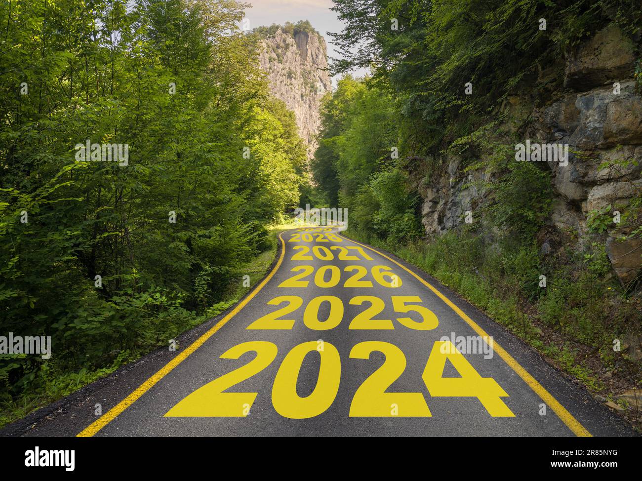 Le mot 2024 écrit sur la route au milieu d'une route forestière asphaltée vide au lever du ...