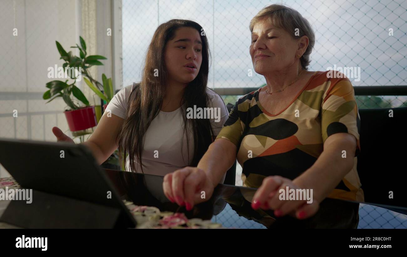 Grand-mère joyeuse devant une tablette avec sa petite-fille asiatique ...