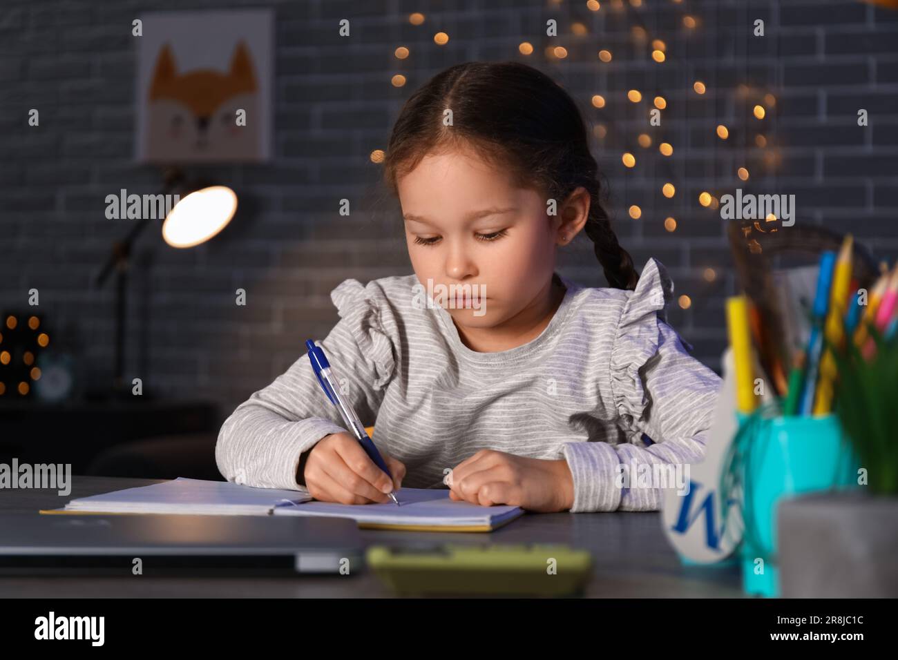 Petite fille qui fait des leçons à la maison tard dans la soirée Photo ...