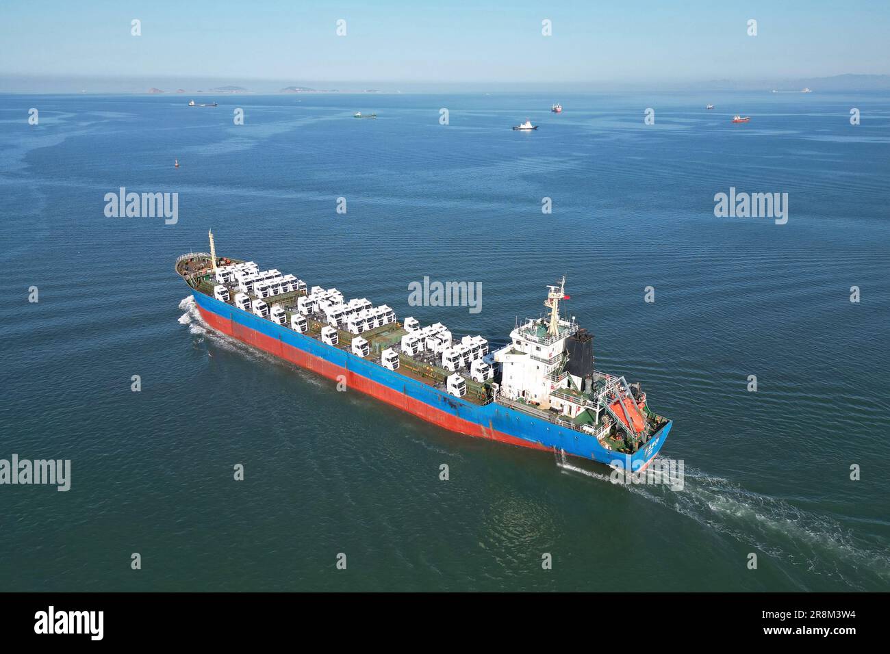 YANTAI, CHINE - le 21 JUIN 2023 - Un cargo chargé de poids lourds de fabrication chinoise quitte ...