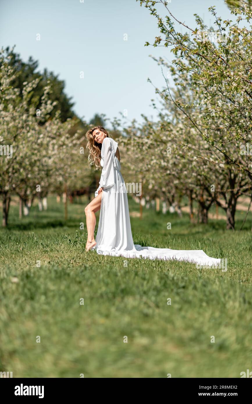 Jardin blond fleuri. Une femme vêtue d'une robe blanche se promène dans ...