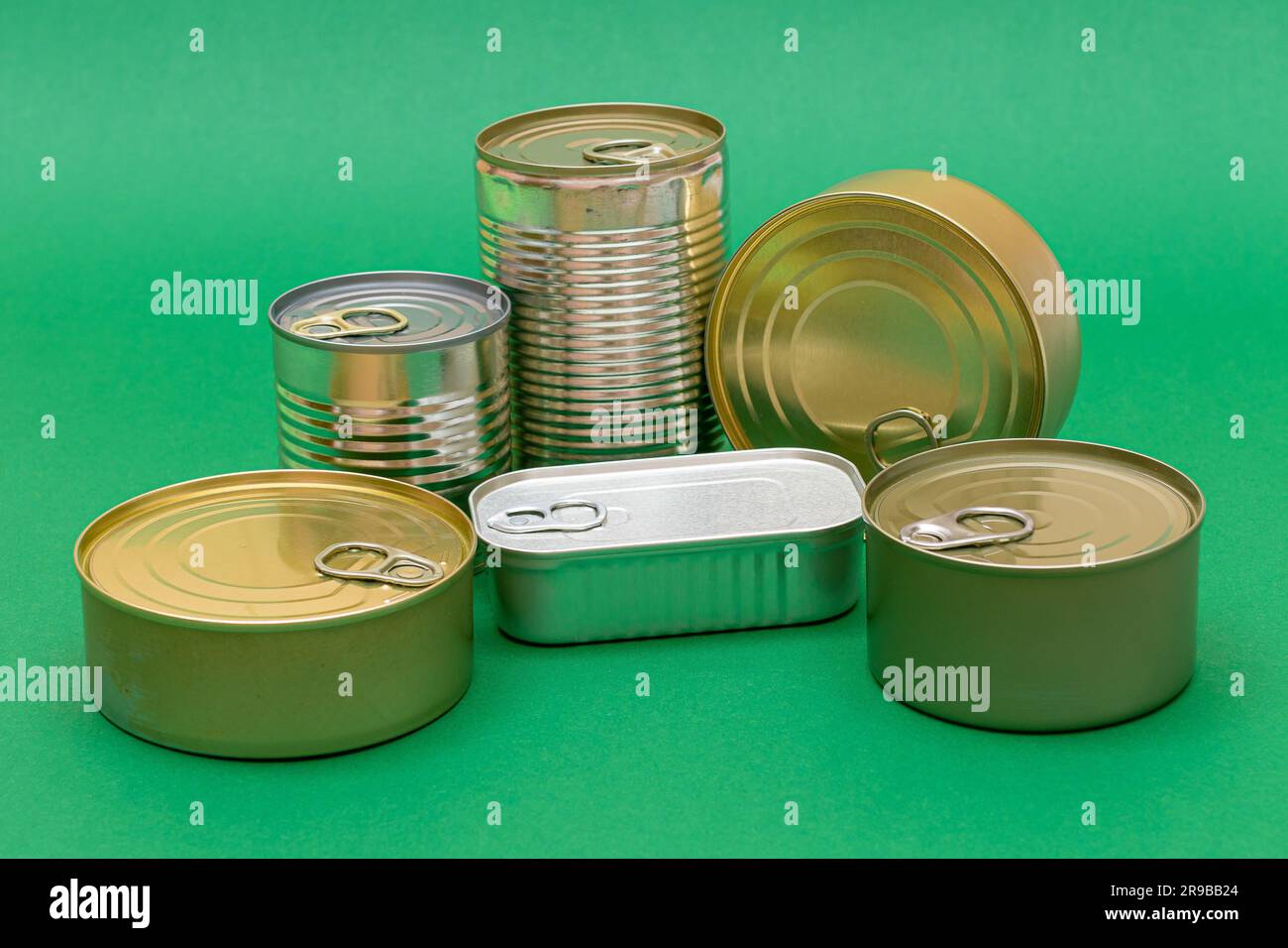 Groupe de boîtes en étain empilées avec bords vides sur fond vert ...