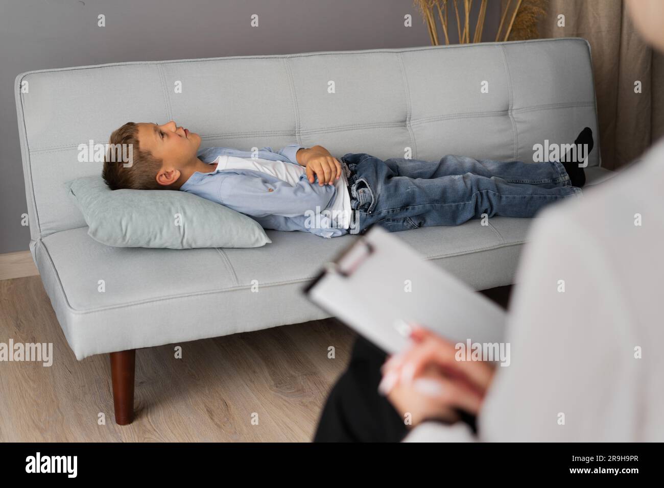 Psychologue féminine notant tandis que son petit patient parle de ses ...