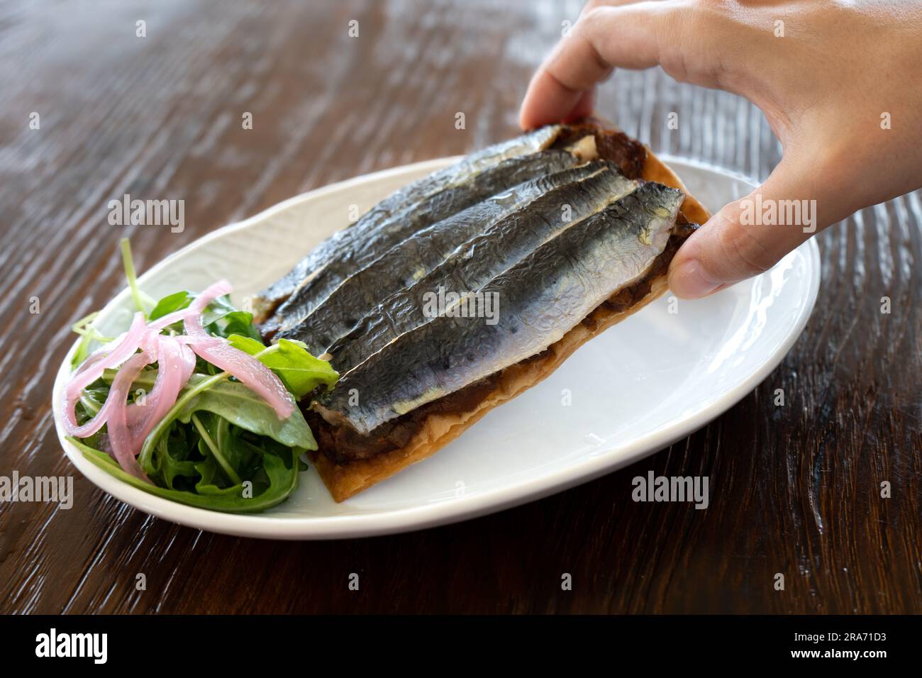 Gros plan de la main d'une femme prenant un toast sardine de style ...