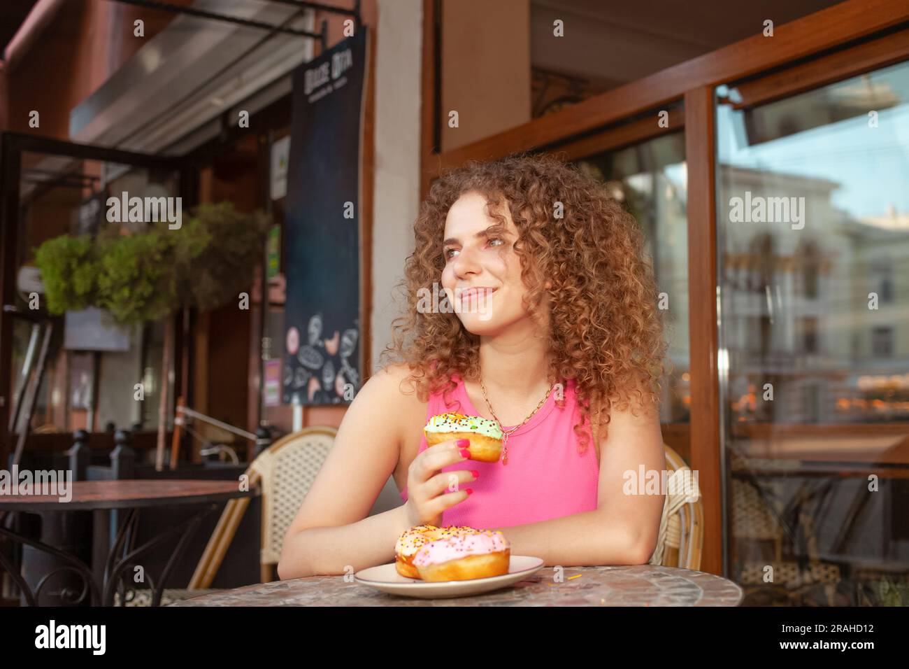 Portrait de belle jeune femme frisée dans le café sur la terrasse d'été ...