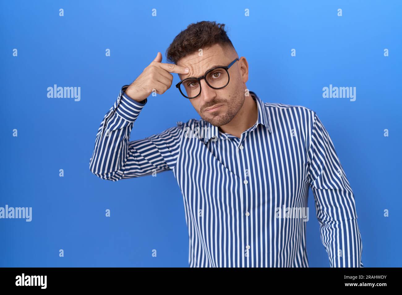 Homme hispanique avec la barbe portant des lunettes pointant malheureux ...