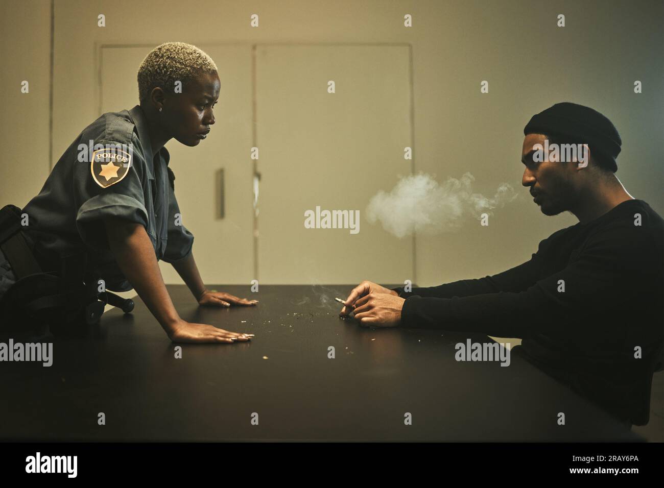 Homme, fumant et détective parlant dans la salle d'interrogatoire avec ...