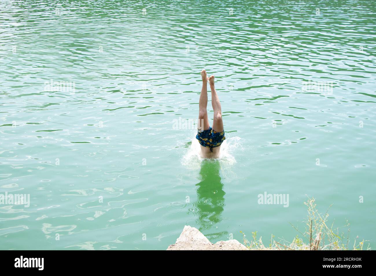 Un homme plonge dans l'eau dans une carrière, les pieds dans l'eau, l ...