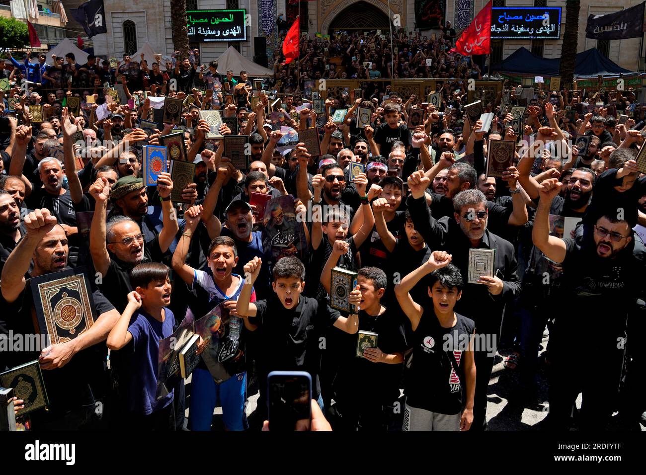 Hezbollah supporters chant slogans as they raise the Quran during a ...