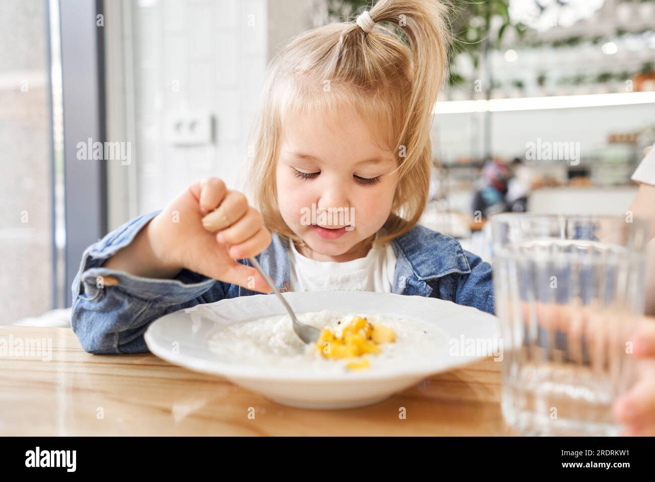 Adorable fille qui boit de l'eau fixe, mangeant du porridge de riz à la ...