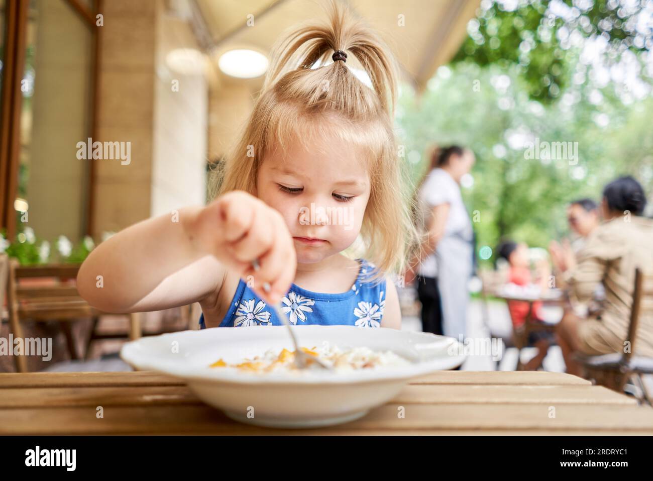 Petit enfant prenant le petit déjeuner au café. Adorable fille qui boit ...