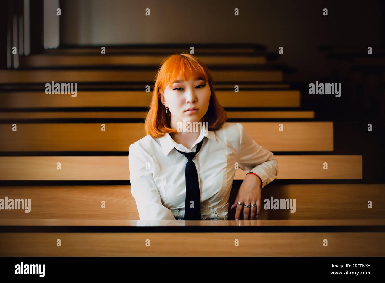 Une jeune, belle étudiante asiatique aux cheveux roux en uniforme est ...