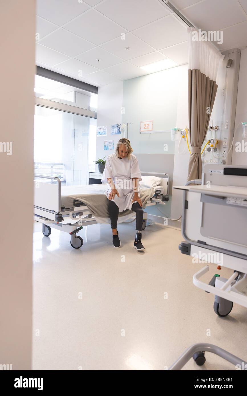 Patiente caucasienne âgée avec prothèse de jambe assise sur le lit à l'hôpital Photo Stock - Alamy
