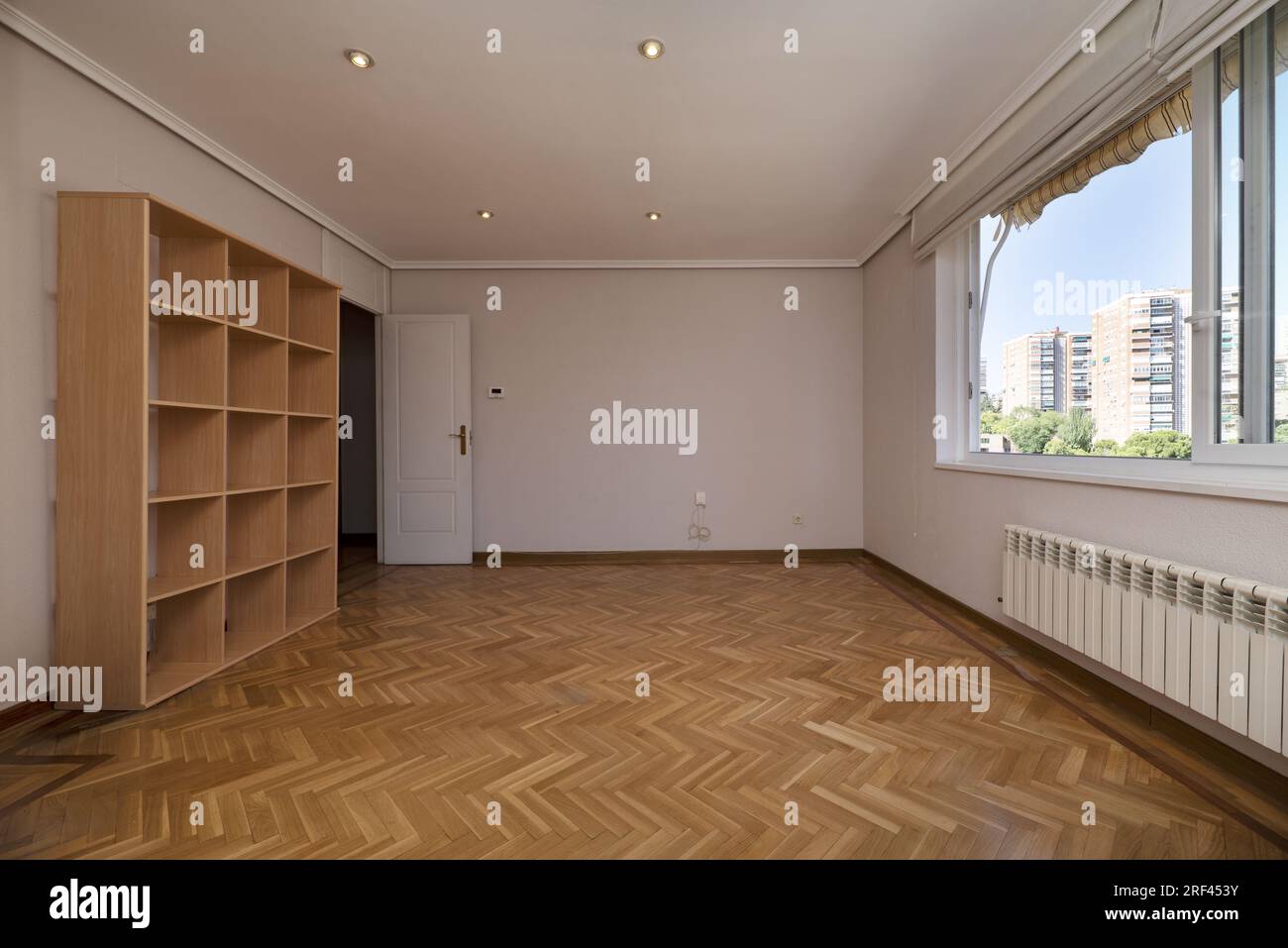 Salon vide avec une bibliothèque en bois coloré sur un mur et une ...