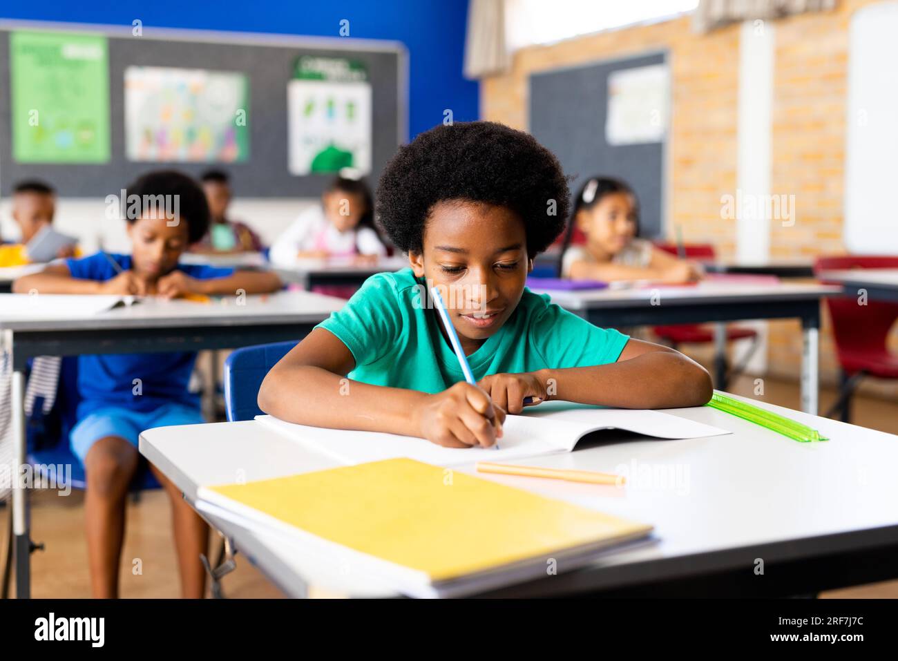 Portrait d'un bon élève afro-américain écrit dans un carnet au bureau ...