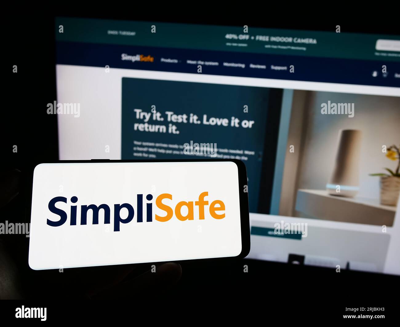 Personne tenant le téléphone mobile avec le logo de la société américaine de sécurité à domicile ...