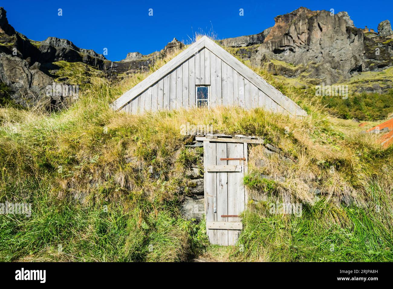 Une dépendance rurale avec une porte en bois est entourée d'une ...